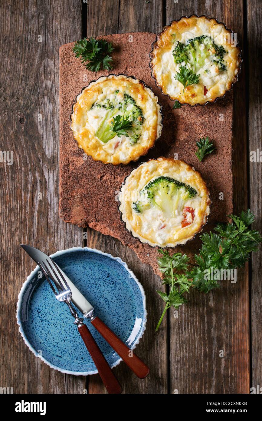 Baked homemade quiche pie in mini metal forms served with fresh greens ...