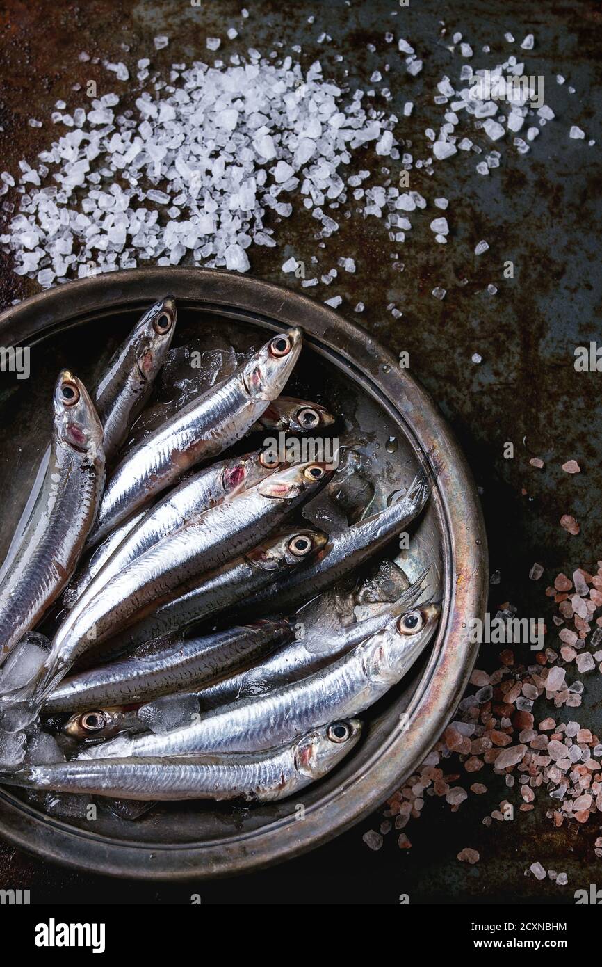 Lot of raw fresh anchovies fishes on crushed ice in vintage plate with ...