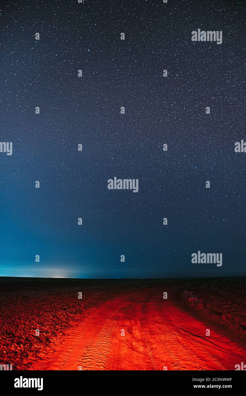 Night Starry Sky With Glowing Stars Above Country Road Is Lit In Red ...