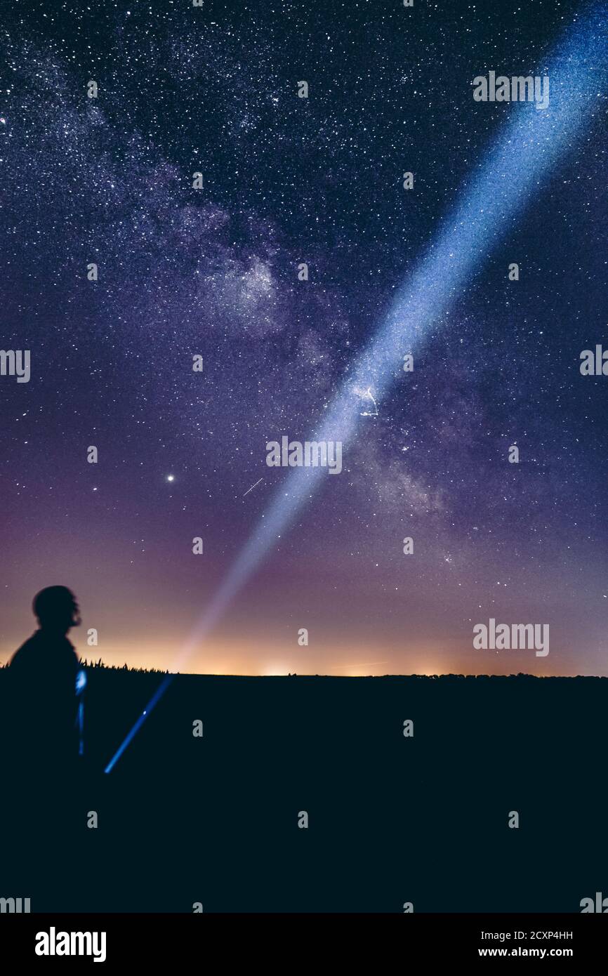 Vertical shot of a person pointing the flashlight at the sky with the ...