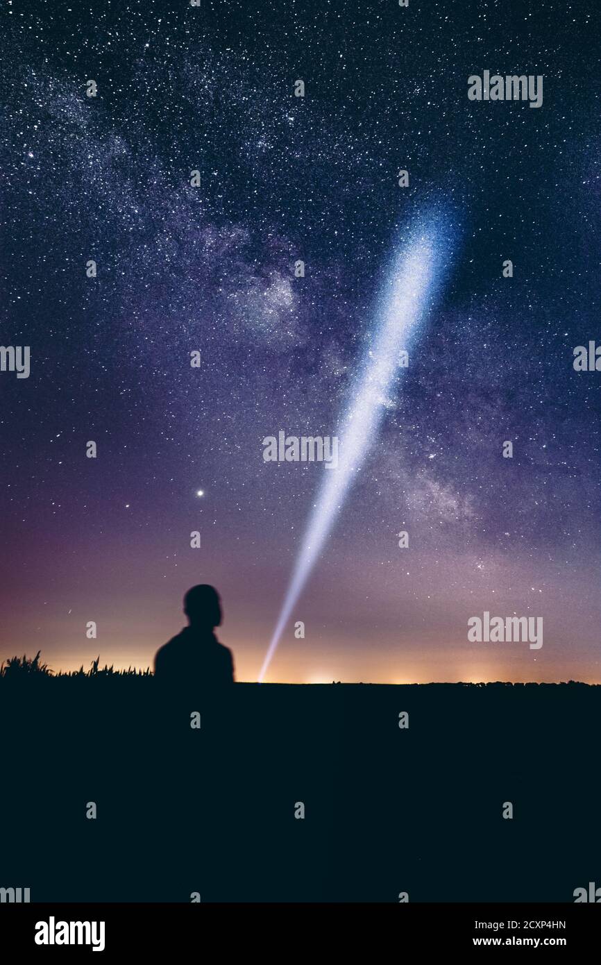 Vertical shot of a person pointing the flashlight at the sky with the ...