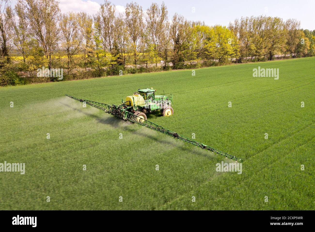 Tractor spraying chemical pesticides with sprayer on the large green ...