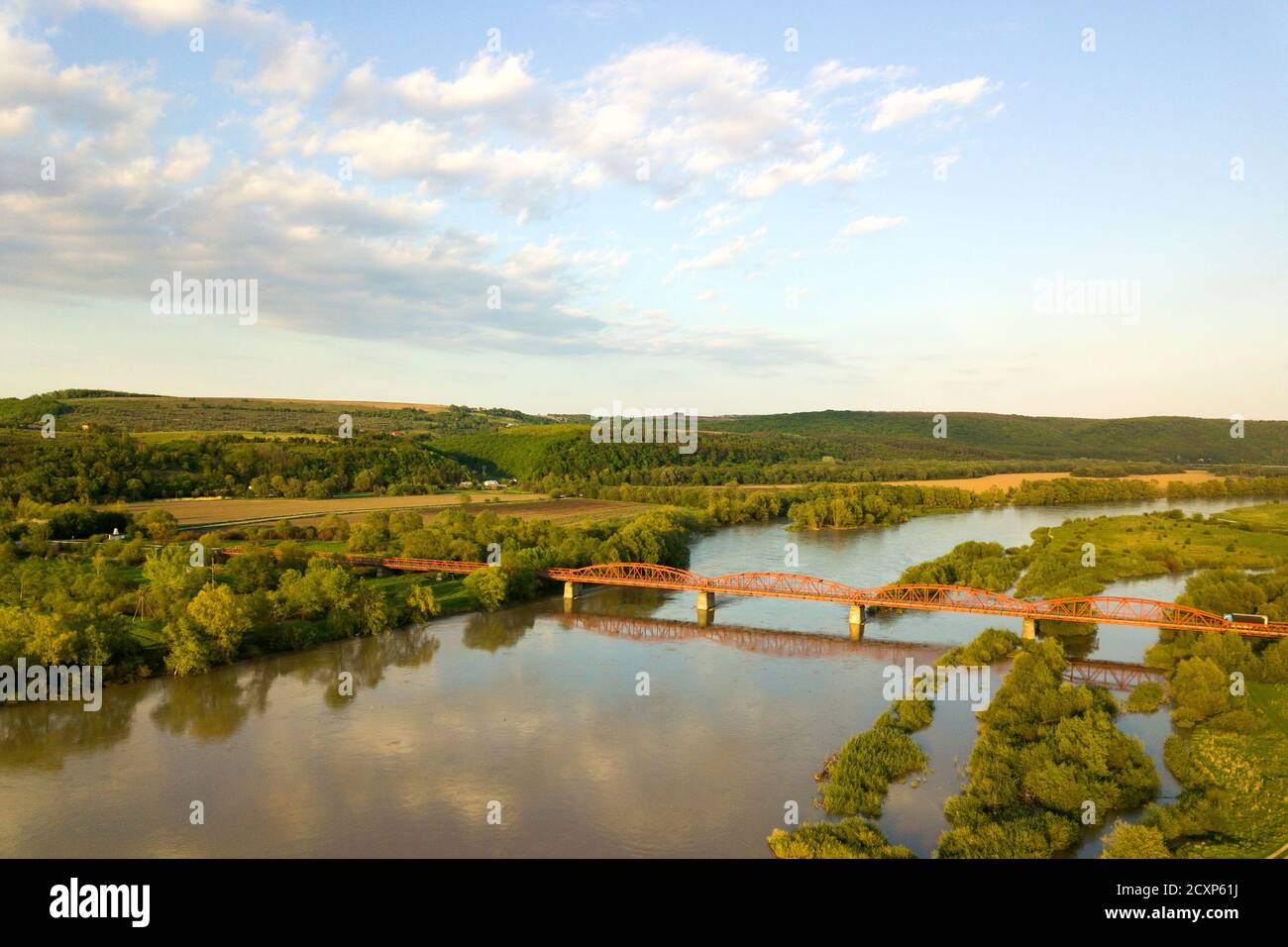 Aerial view of a narrow road bridge stretching over muddy wide river in ...