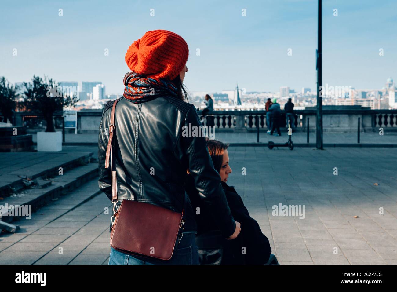 focus on foreground of the back of young woman pushing a wheelchair ...
