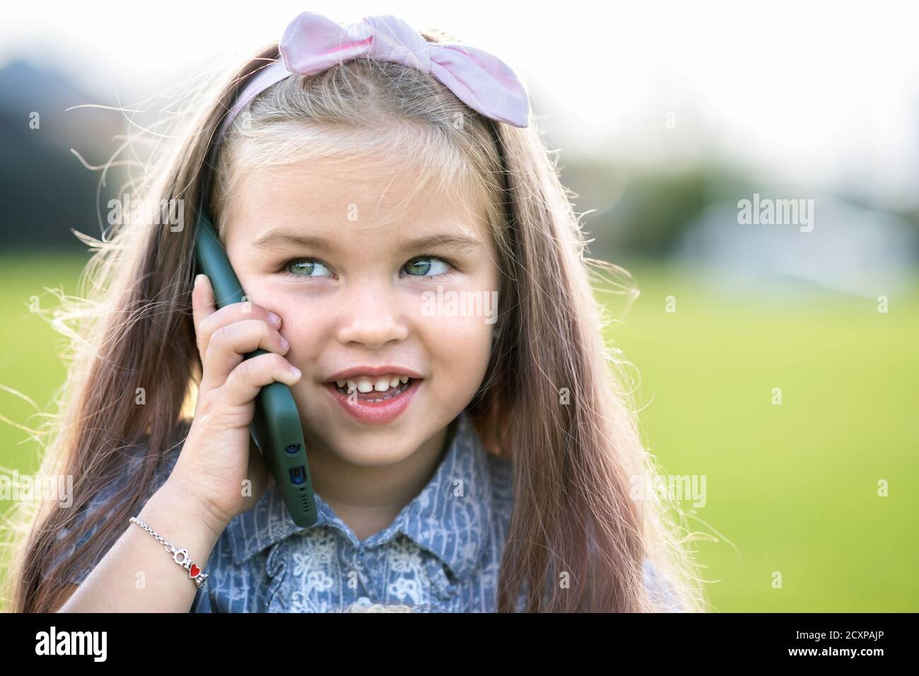 Pretty happy child girl talking on mobile phone smiling outdoors in ...