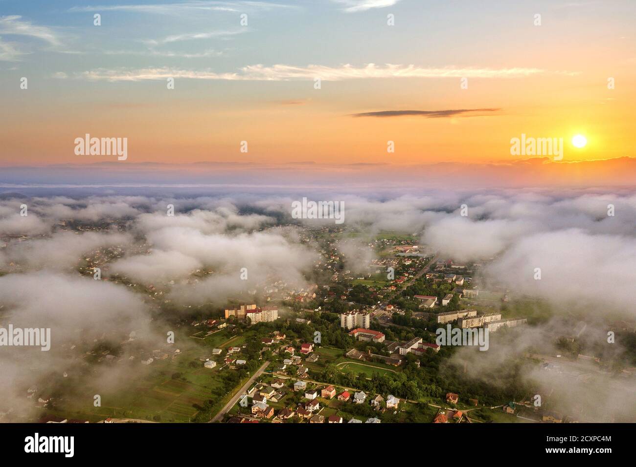 Sunset over rural area in town with clouds and yellow sun Stock Photo ...