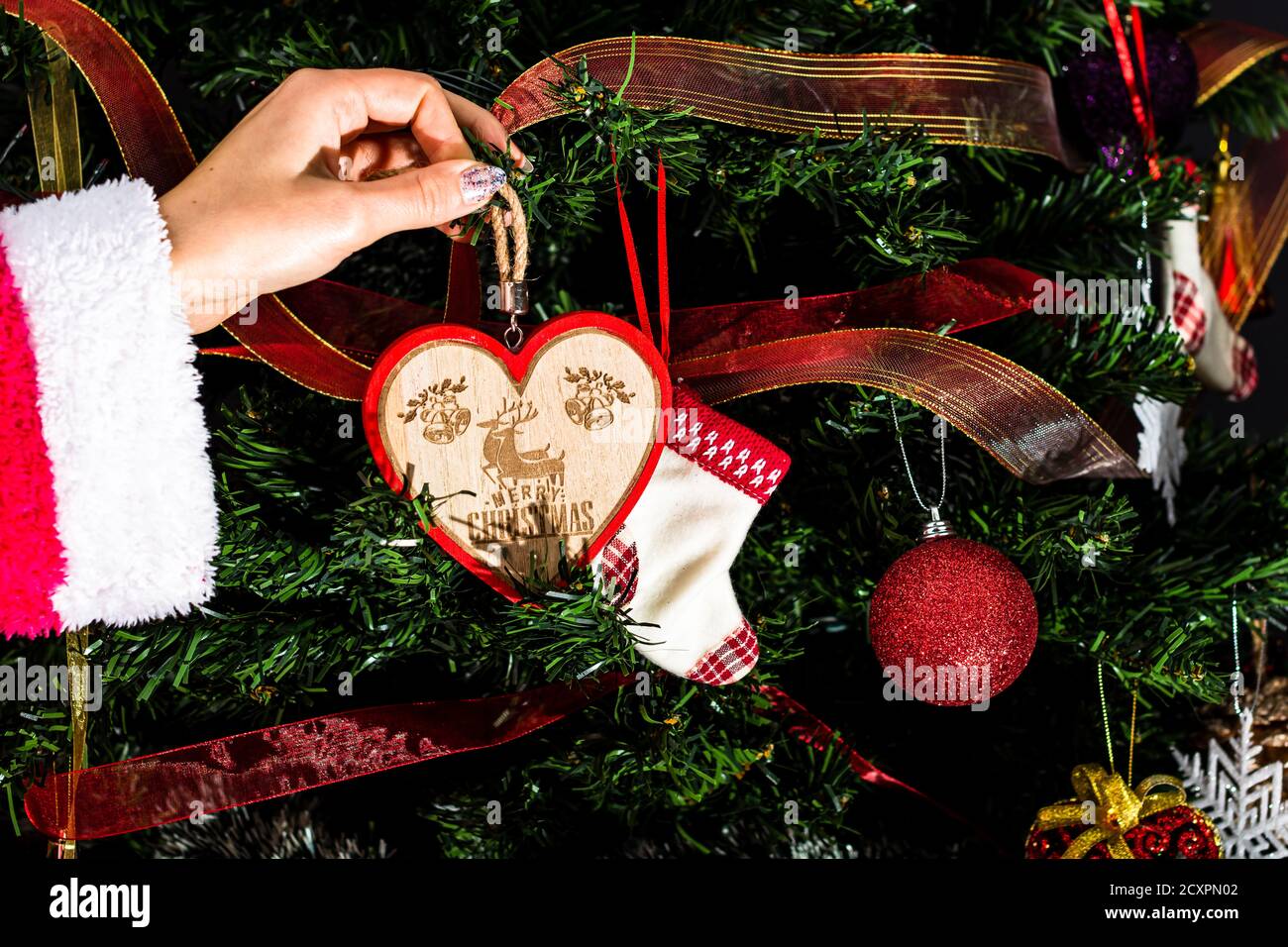 Decorating Christmas tree, hand putting Christmas decorations on fir ...