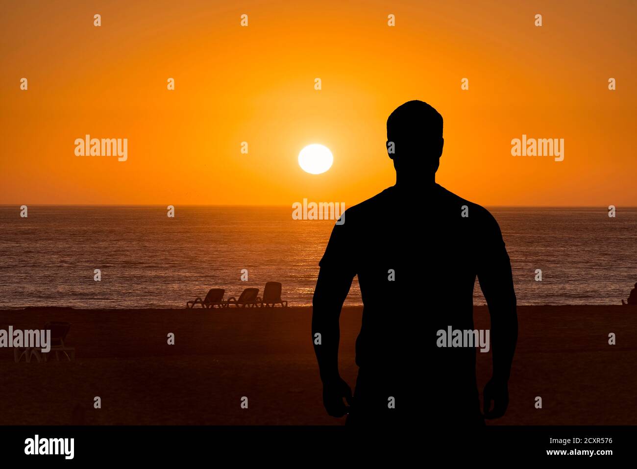 Silhouette of man, back side, in front of sea or ocean during sunset ...