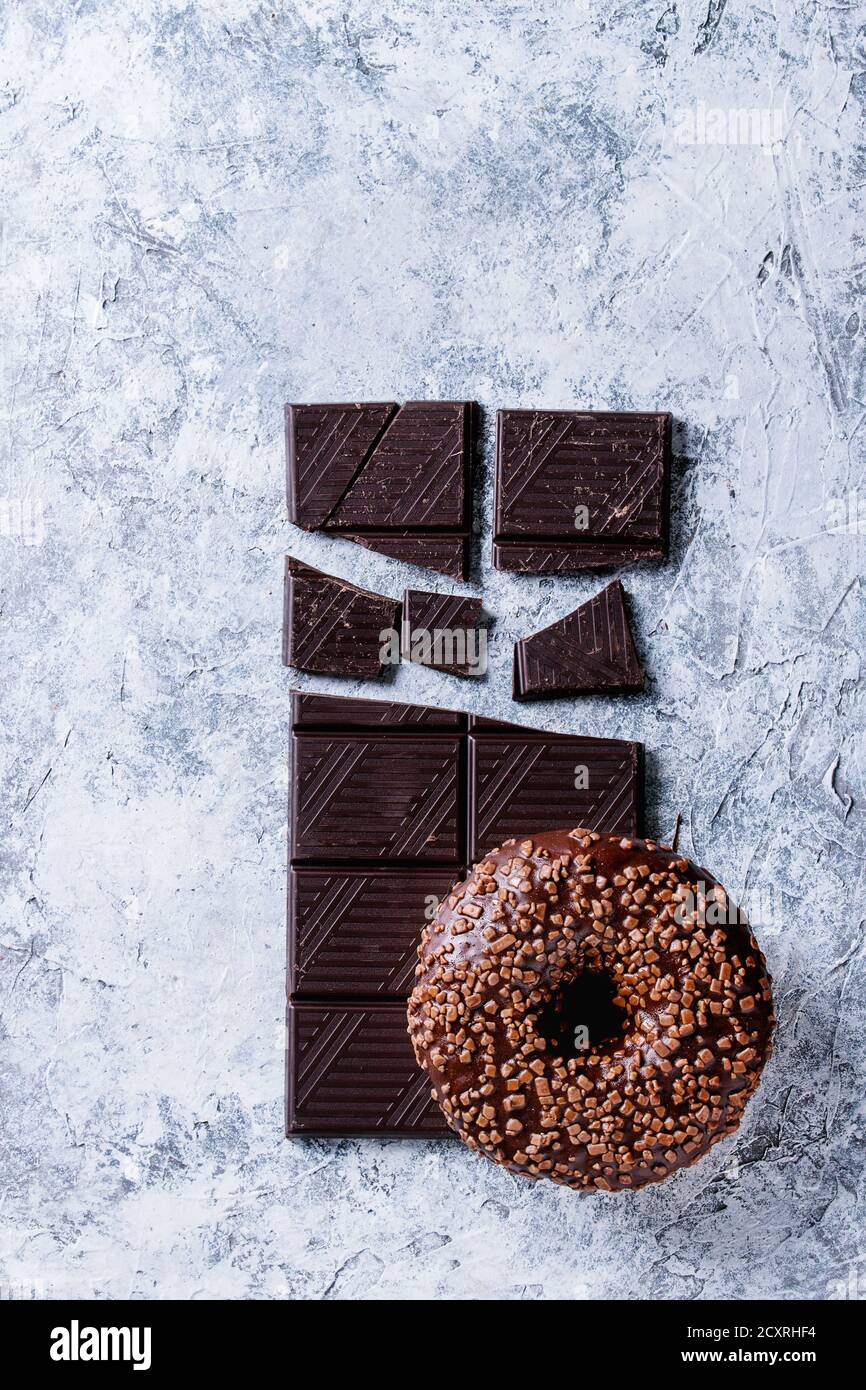 Chocolate glazed donut on chopped chocolate over gray texture ...