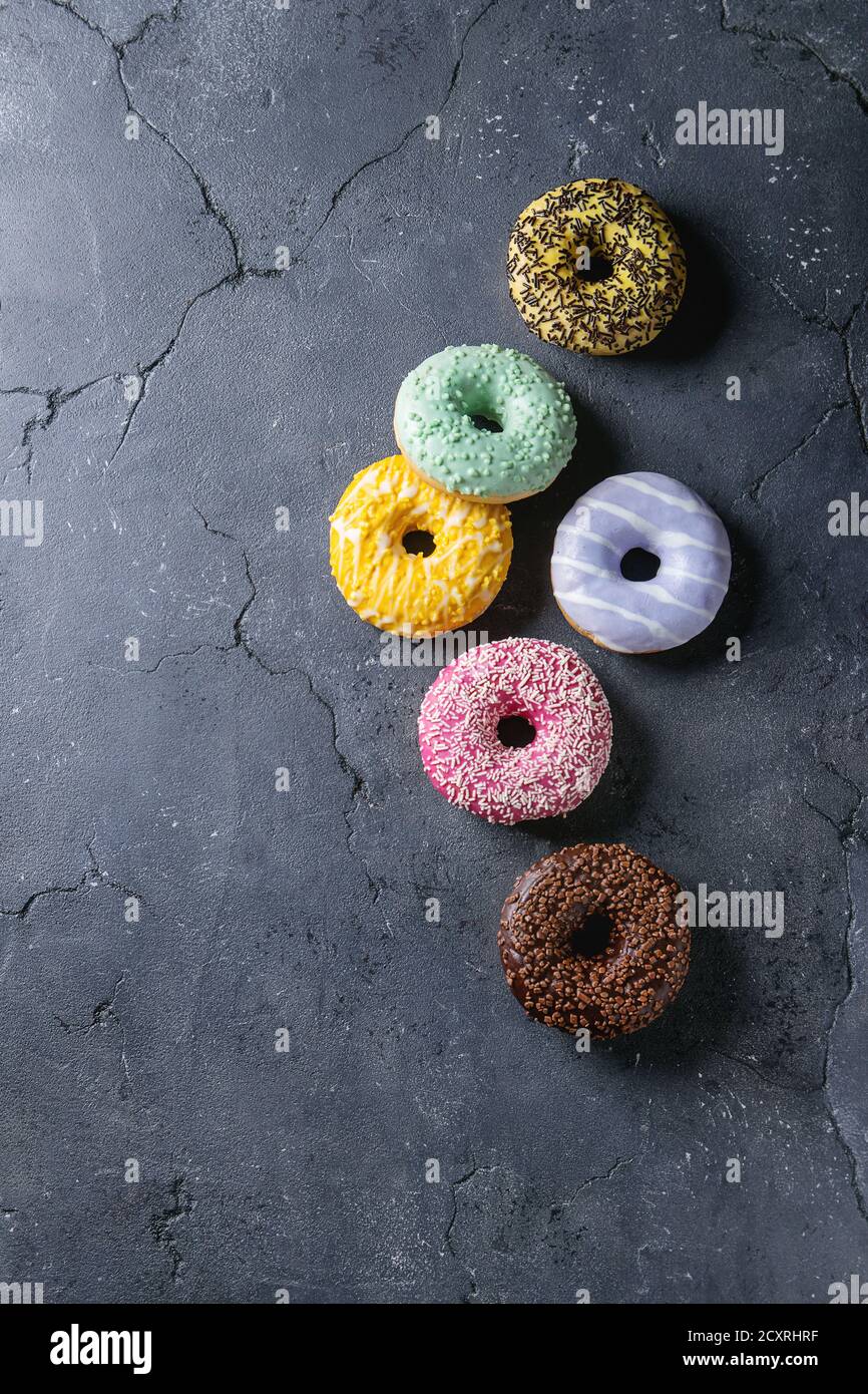 Variety of colorful glazed donuts over black texture background. Top ...