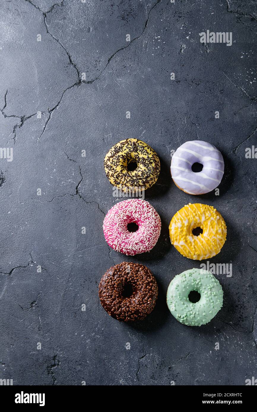 Variety of colorful glazed donuts over black texture background. Top ...