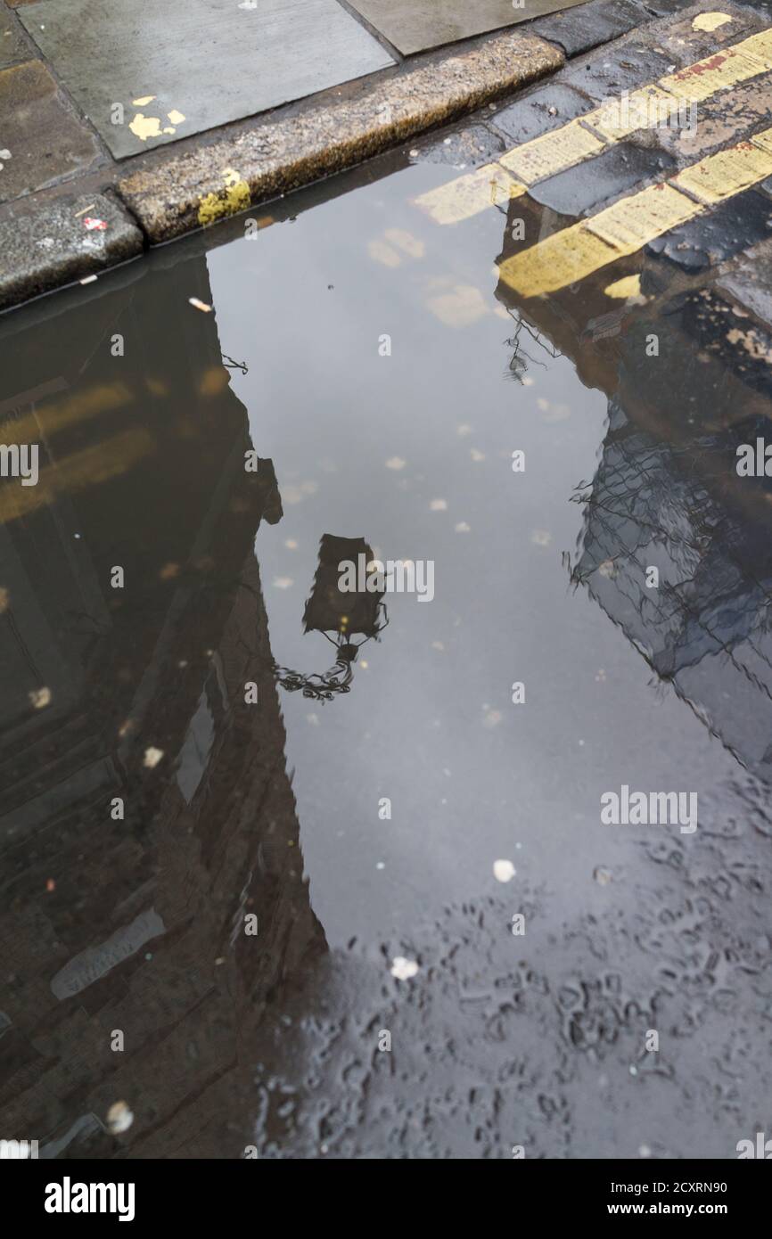 AA puddle with a pub sign reflected in it with double yellow lines on a ...