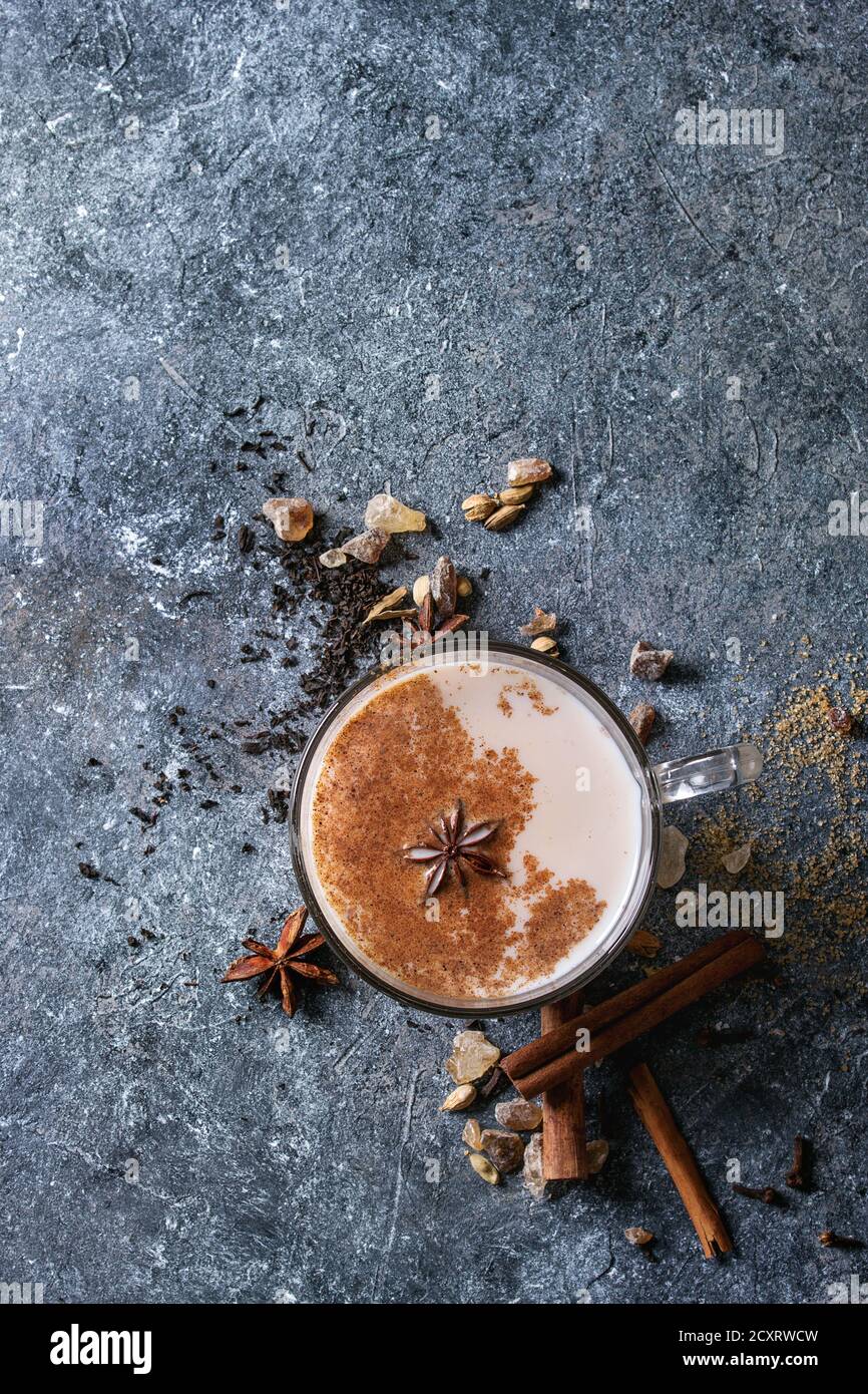 Glass cup of traditional indian masala chai tea with ingredients above ...