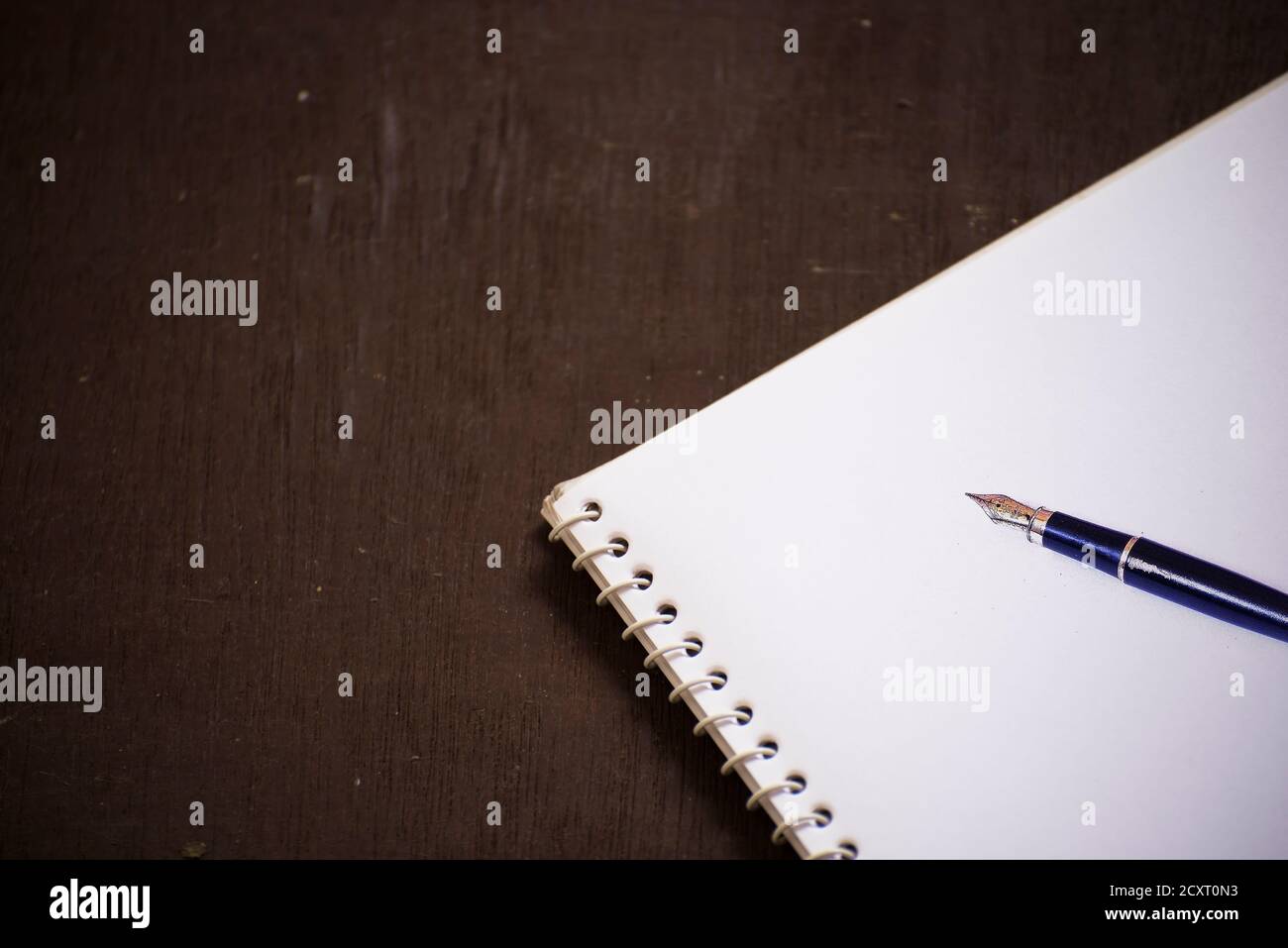 An empty blank white page of a notepad, placed over old wooden ...
