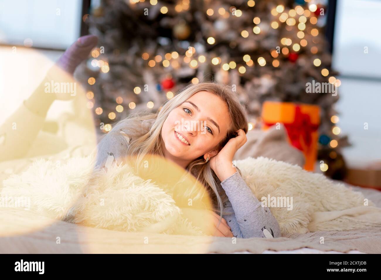 Dreamful cute teen girl near Christmas tree. Kid wearing pajama ...