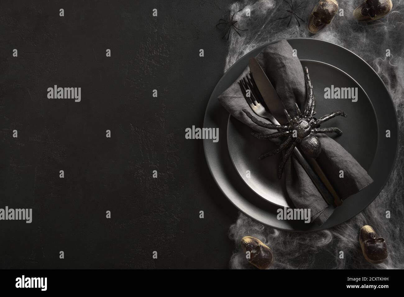 Halloween table setting with skulls , web and spider on black dark ...