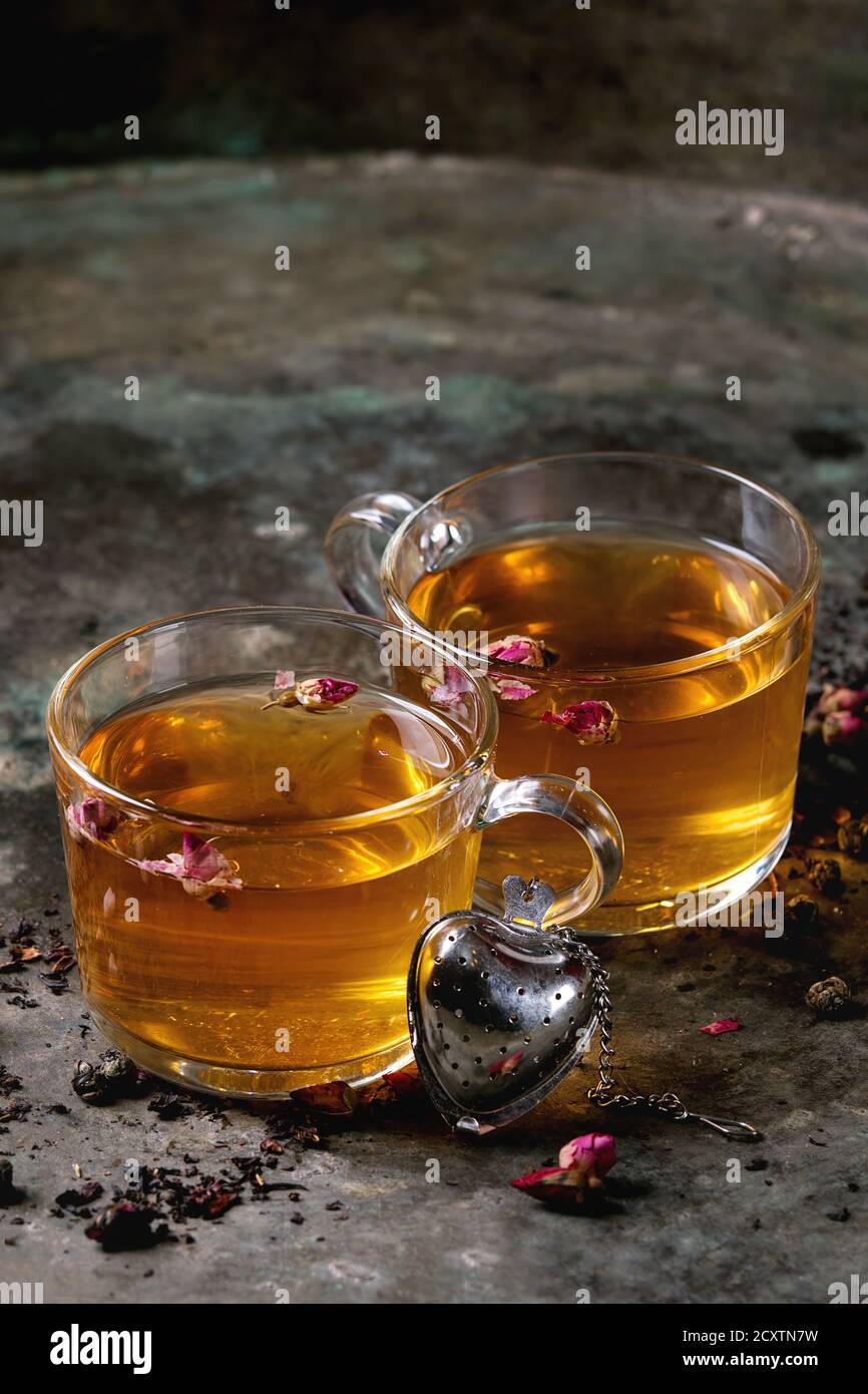 Two glasses of hot tea, rose buds, heart shaped tea strainer, pink ...