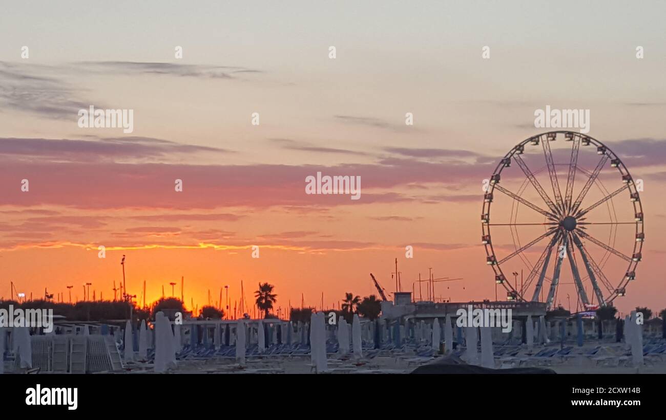 Rimini beach beautiful sunset with ferris wheel Stock Photo - Alamy