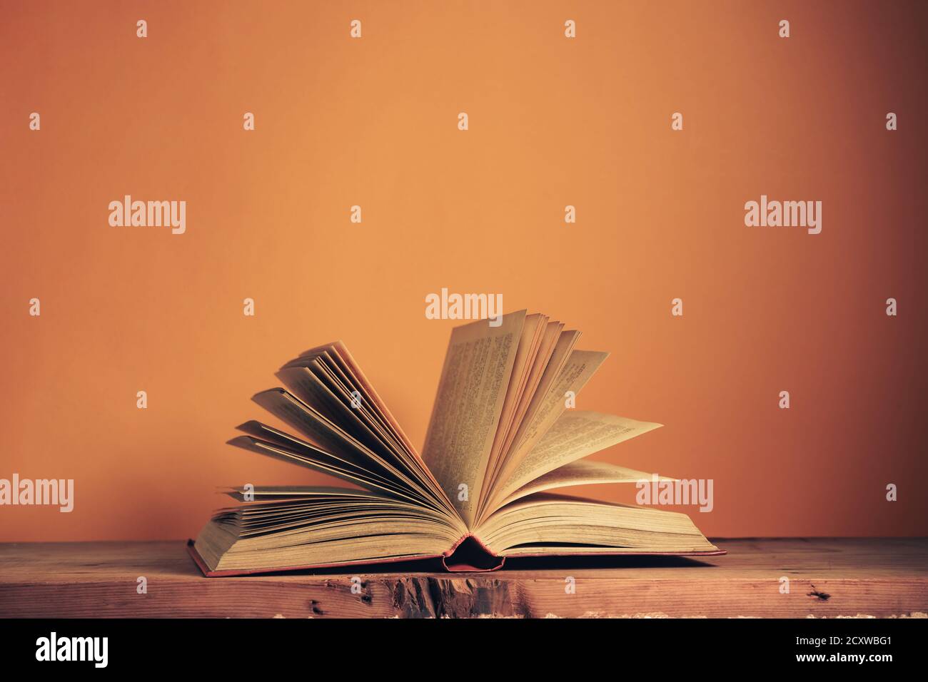 Beautiful ancient open old book on a red wooden table and orange wall ...