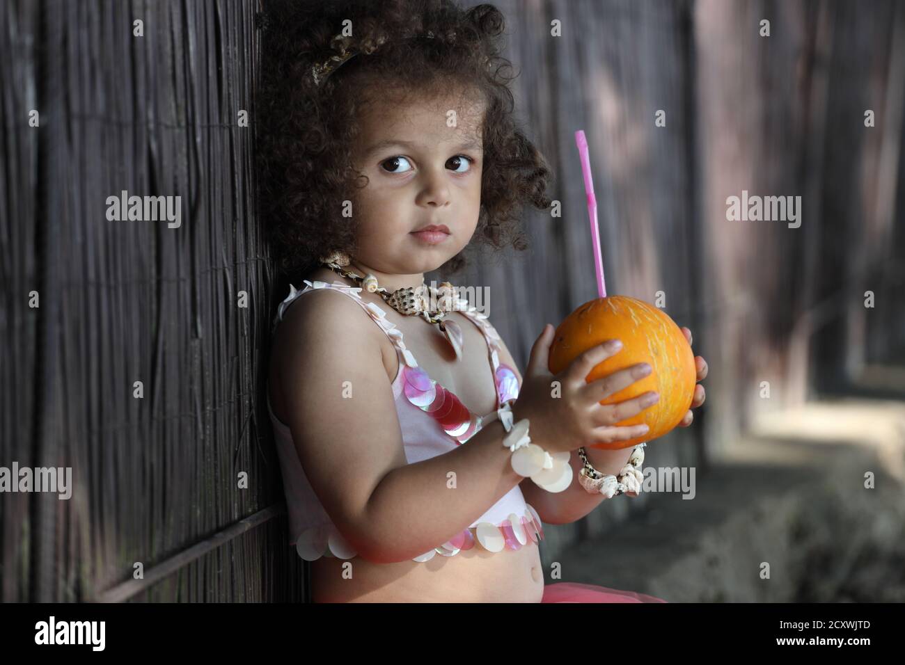 curly girl holding a melon with an inserted tube in her hands. Tropical ...