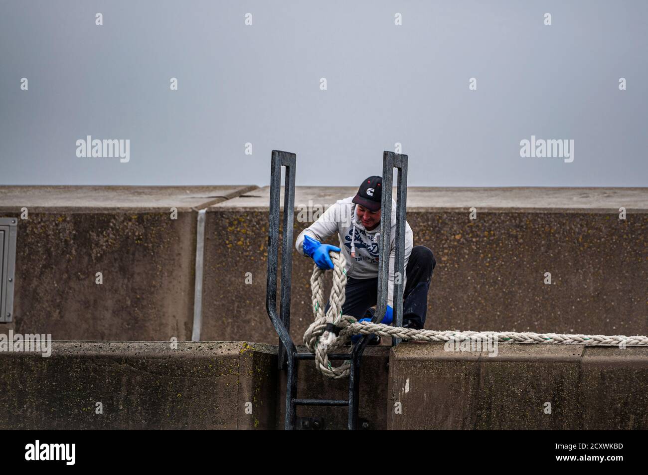 Ropework. Crew member of fishing boat working with heavy mooring line ...