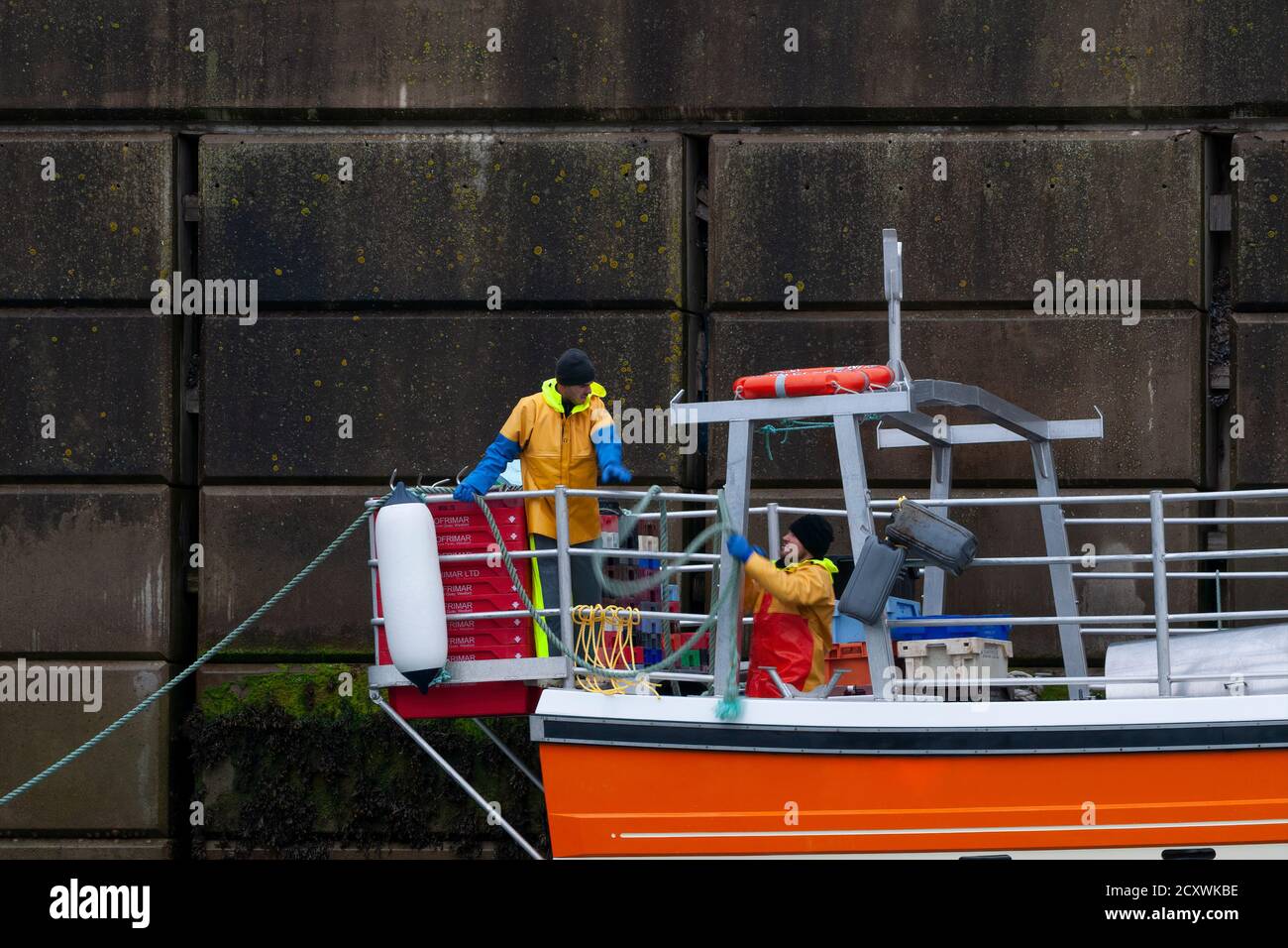 Ropework. Crew of fishing boat working with mooring line Stock Photo ...
