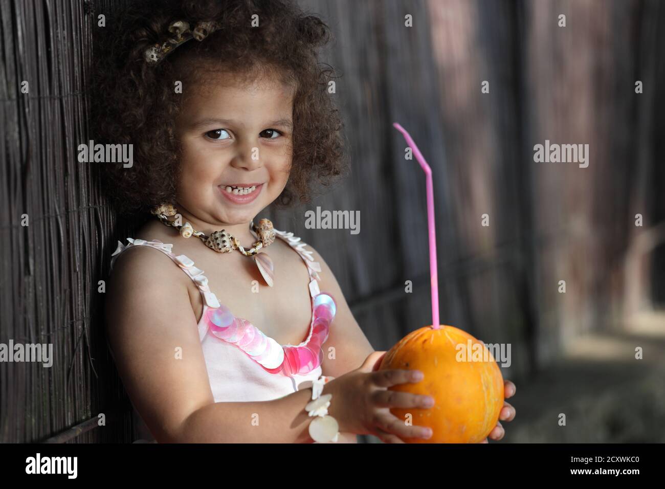 curly girl holding a melon with an inserted tube in her hands. Tropical ...