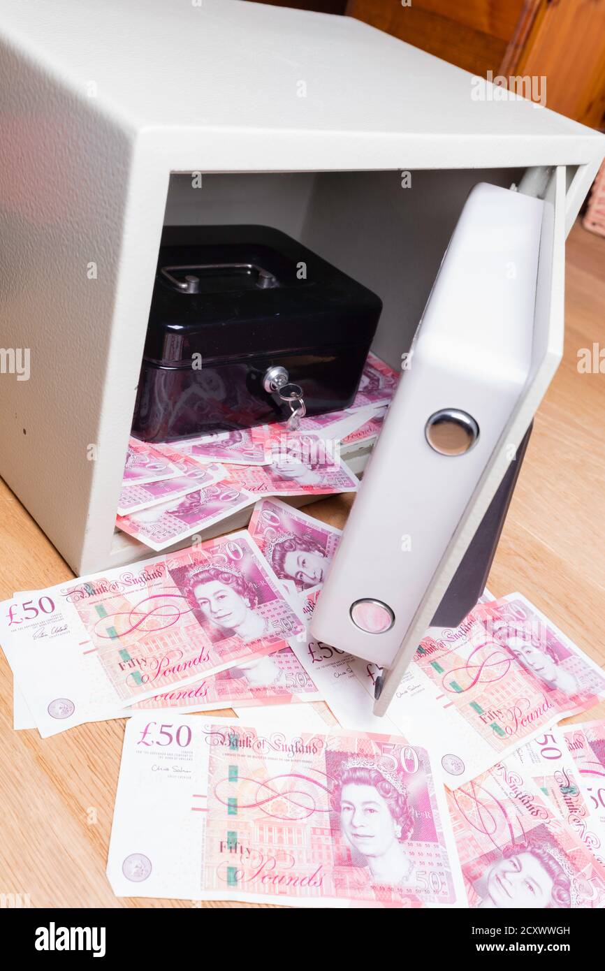 Domestic safe and cash box sitting on floorboards and overflowing with ...
