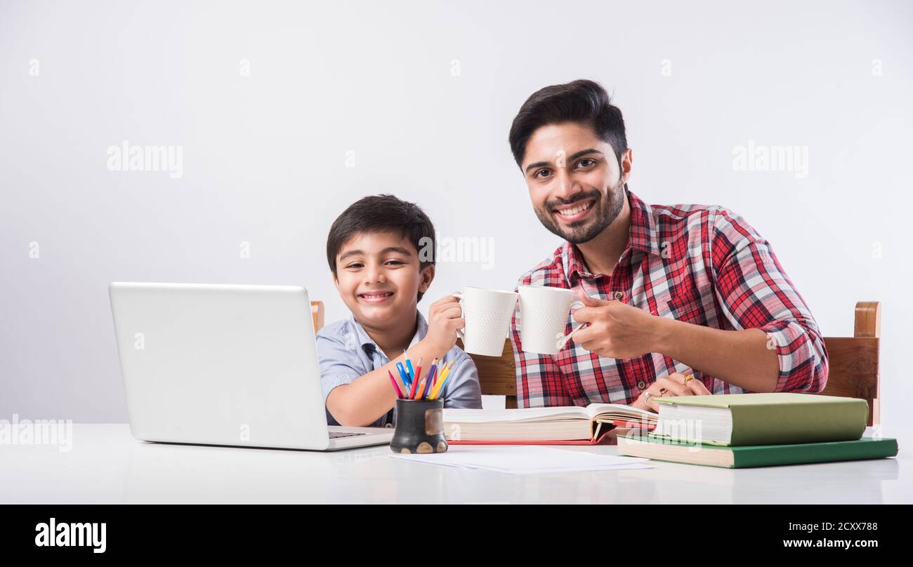 Cute Indian boy with father or male tutor doing homework at home using ...
