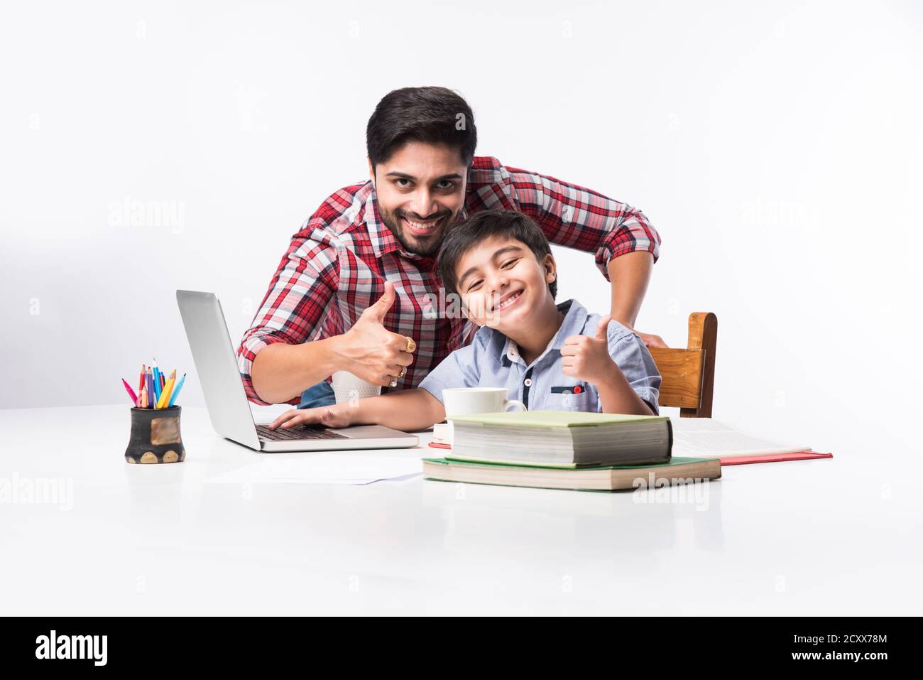Cute Indian boy with father or male tutor doing homework at home using ...