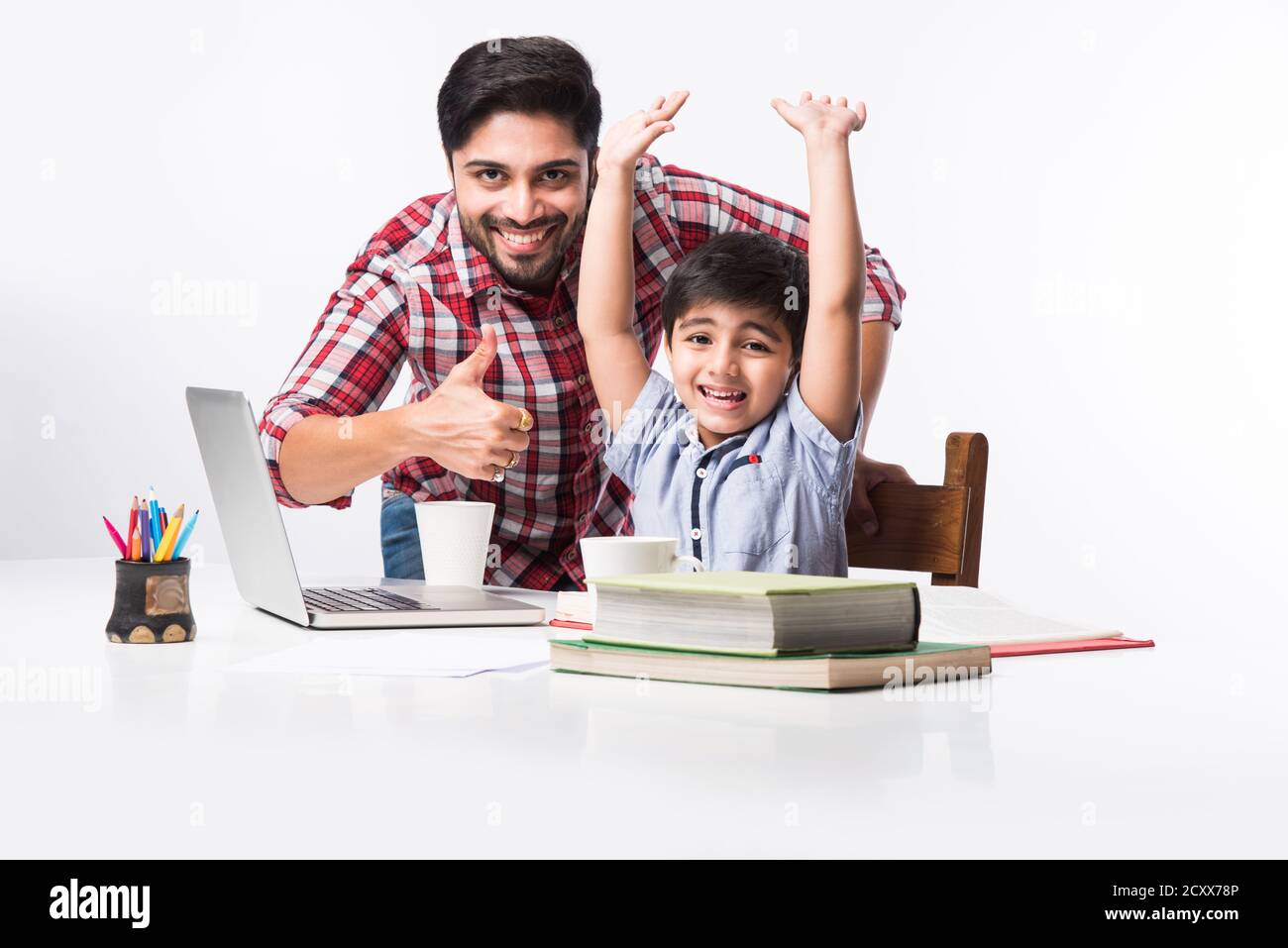 Cute Indian boy with father or male tutor doing homework at home using ...
