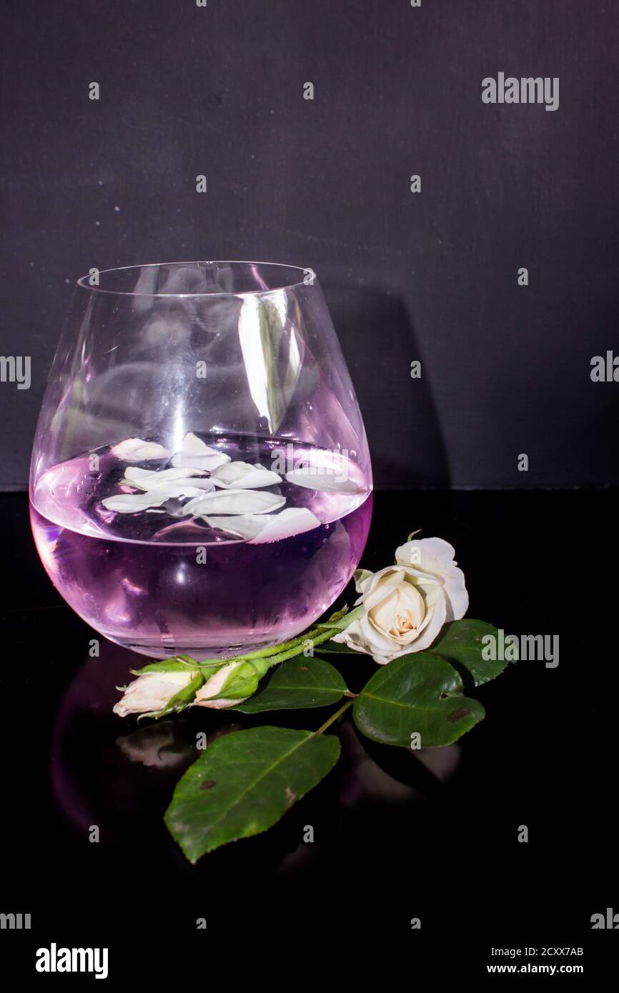 A glass of rose flavored, pink, Gin and Tonic, garnished with white ...