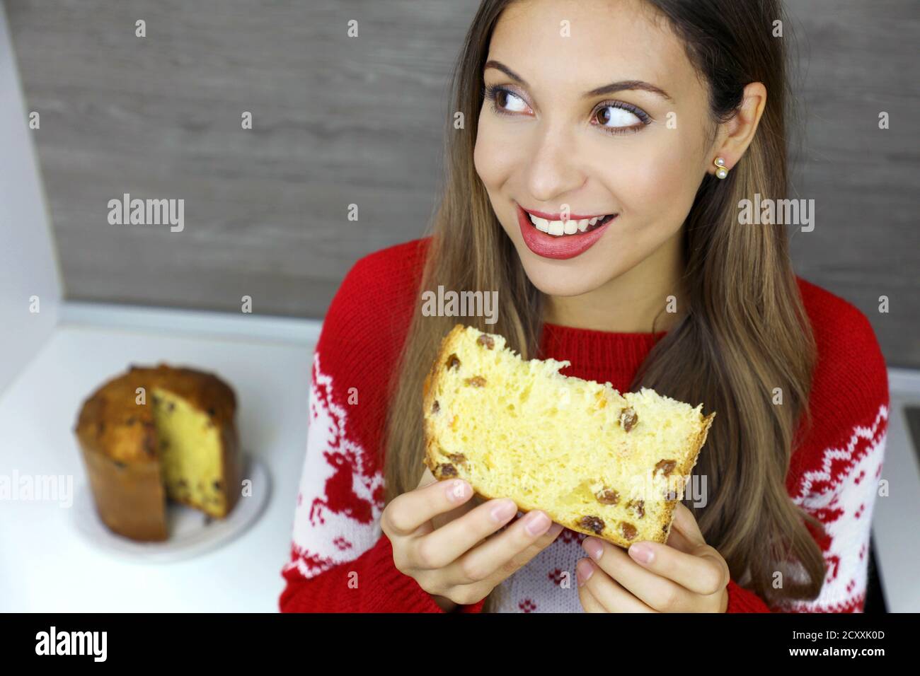 Beautiful young woman eating a slice of Panettone on Christmas holiday ...