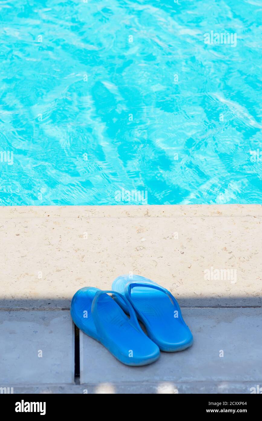 Blue summer flop-flops near edge of swimming pool Stock Photo - Alamy