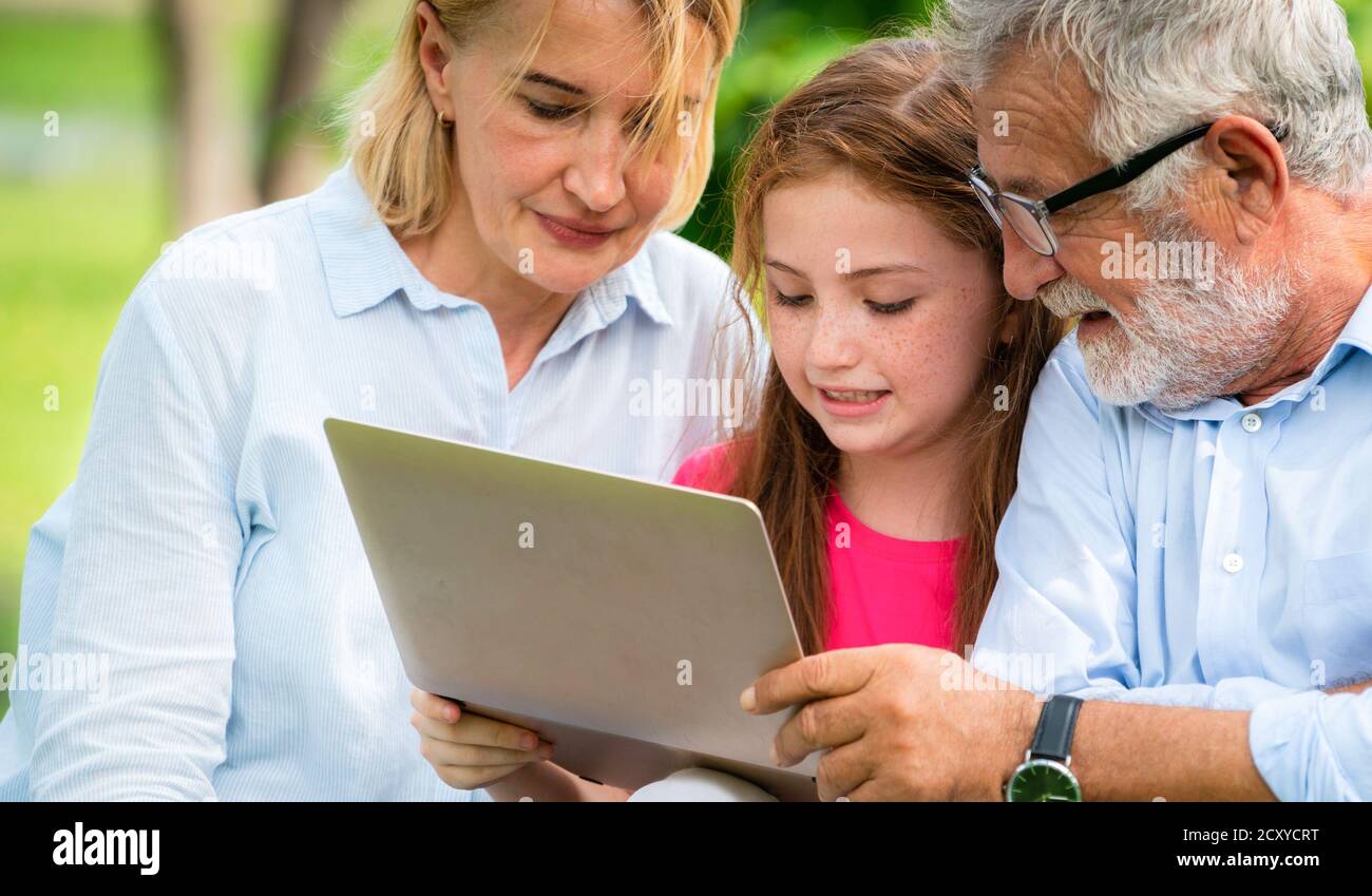 Happy family using laptop computer together in the garden park in ...