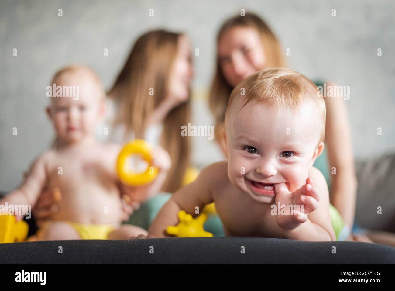 Two young girls play with their cute children in the apartment. Happy ...