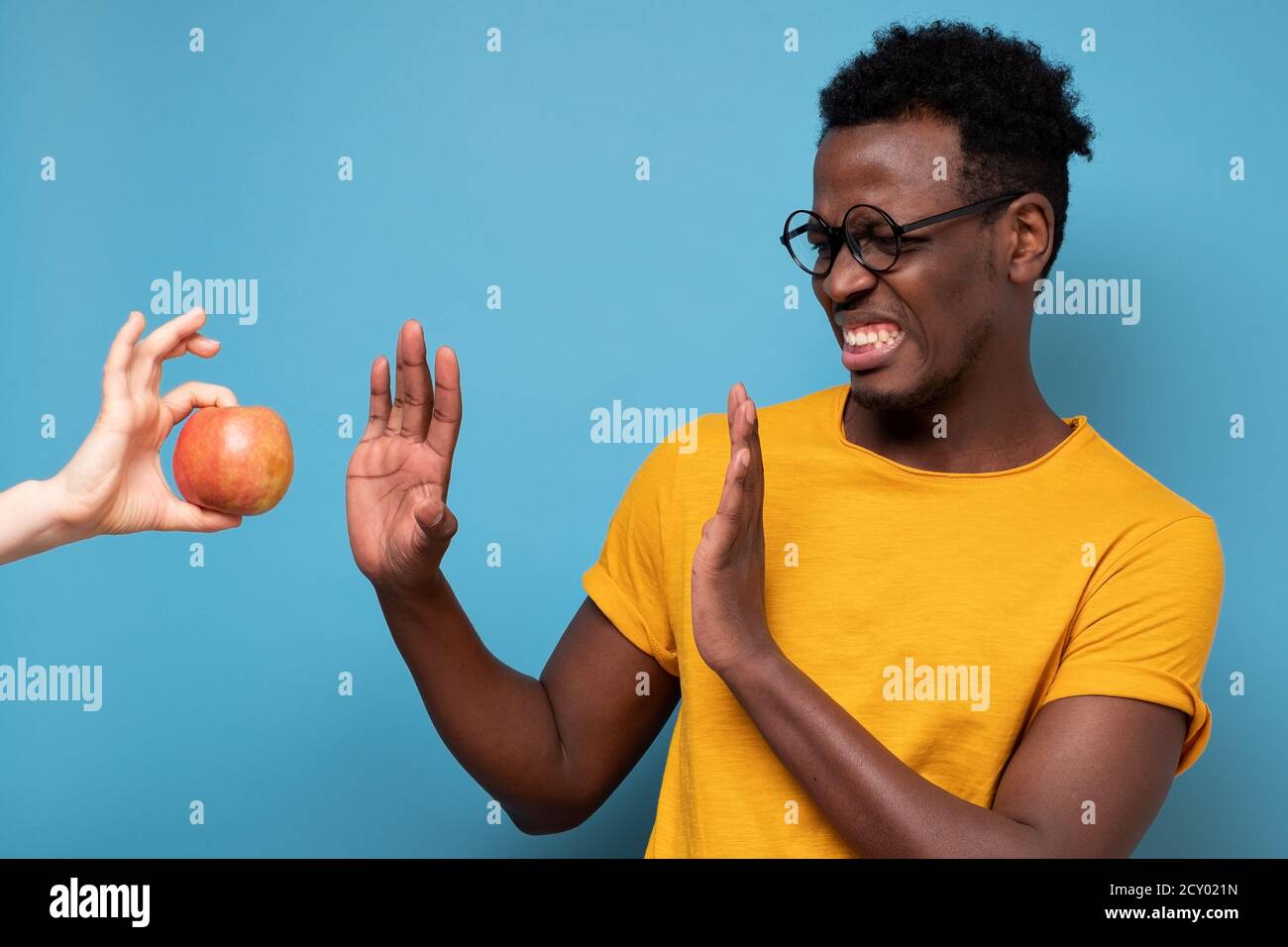 African young man rejecting apple isolated on blue background Stock ...