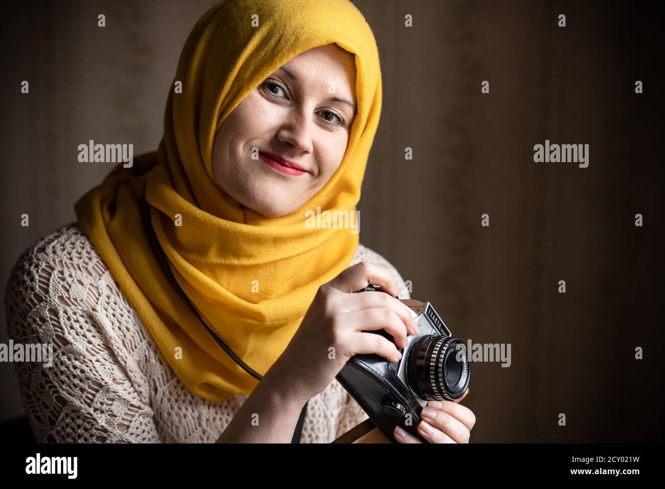 Modern Muslim woman photographer, holds a retro film camera, smiling ...