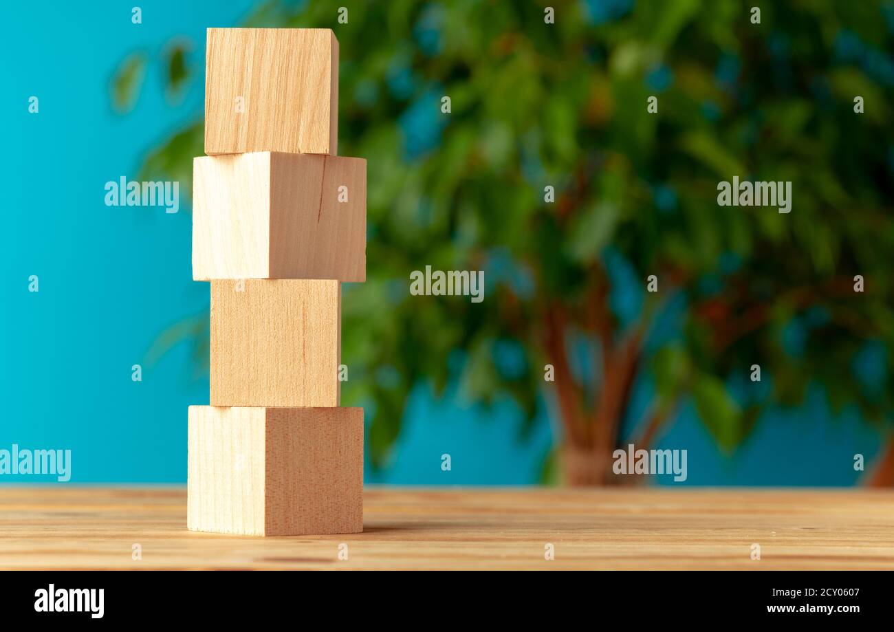 Wooden blocks on desk against blurred plant background Stock Photo - Alamy