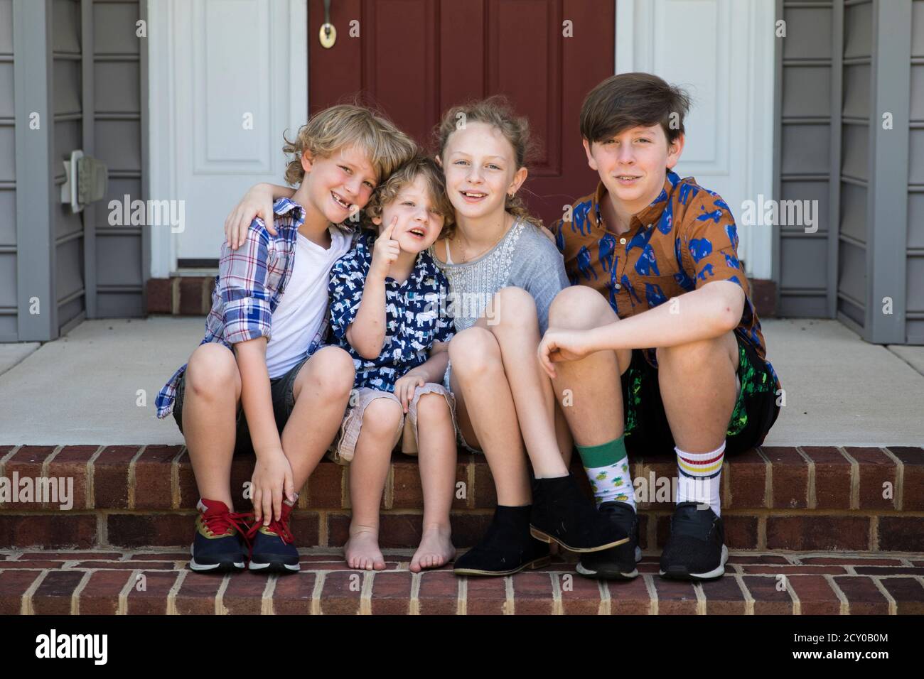 Four Siblings Sit Together on Brick Front Steps in Mismatched Outfits ...
