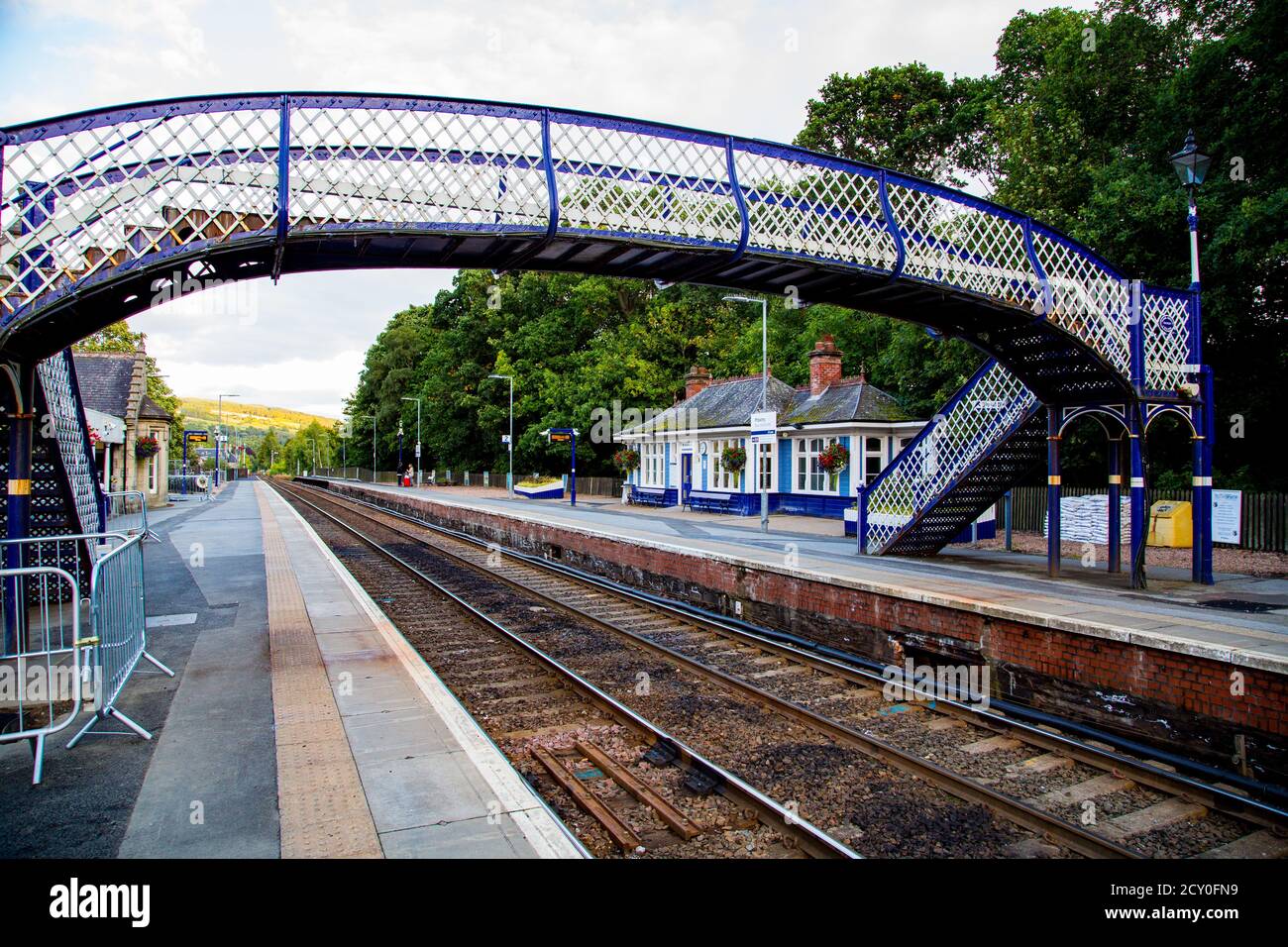 White and blue pedestrian bridge with ornaments over train track Stock ...