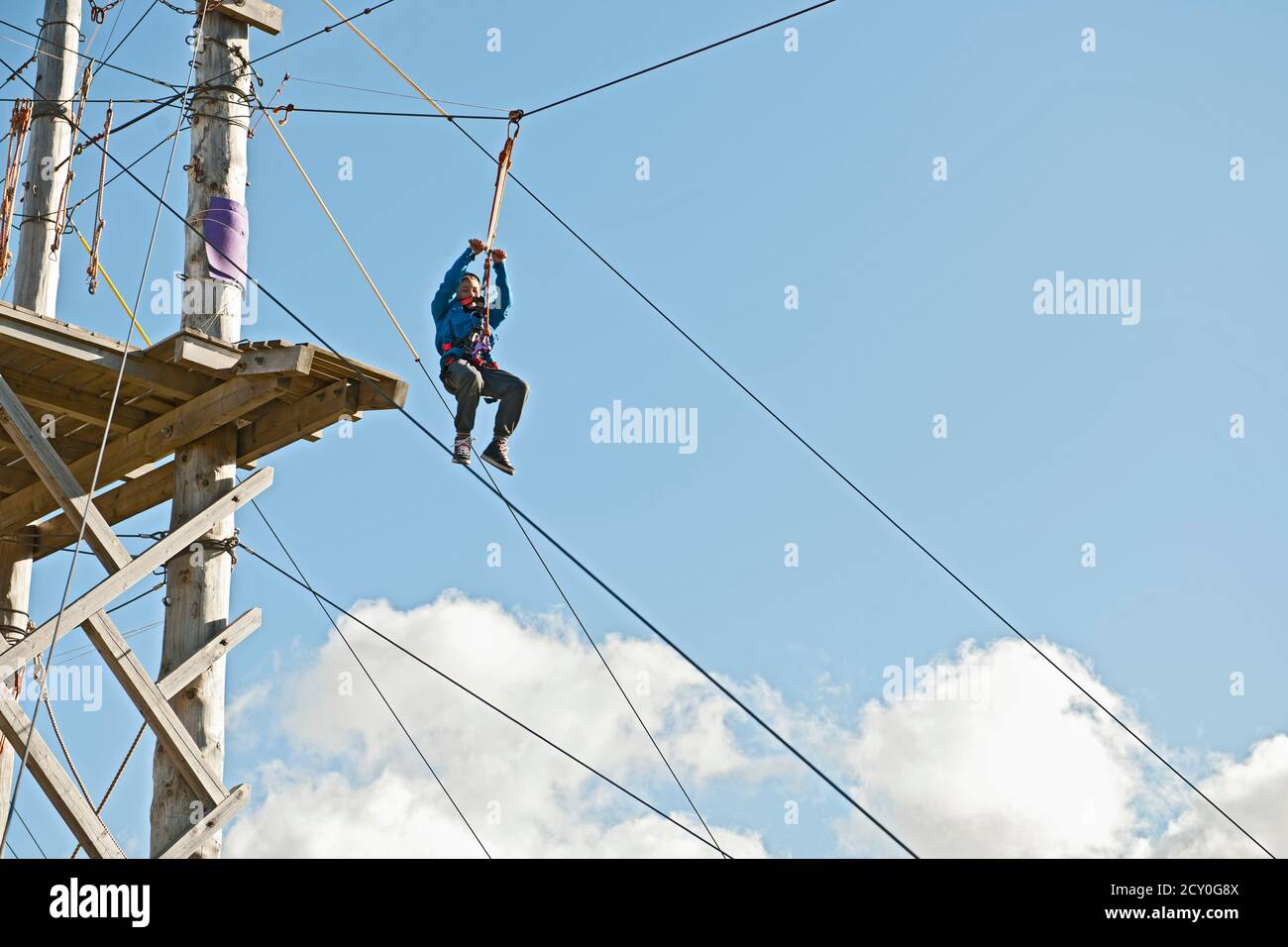 boy going down on a zip line at high rope access course in Iceland ...