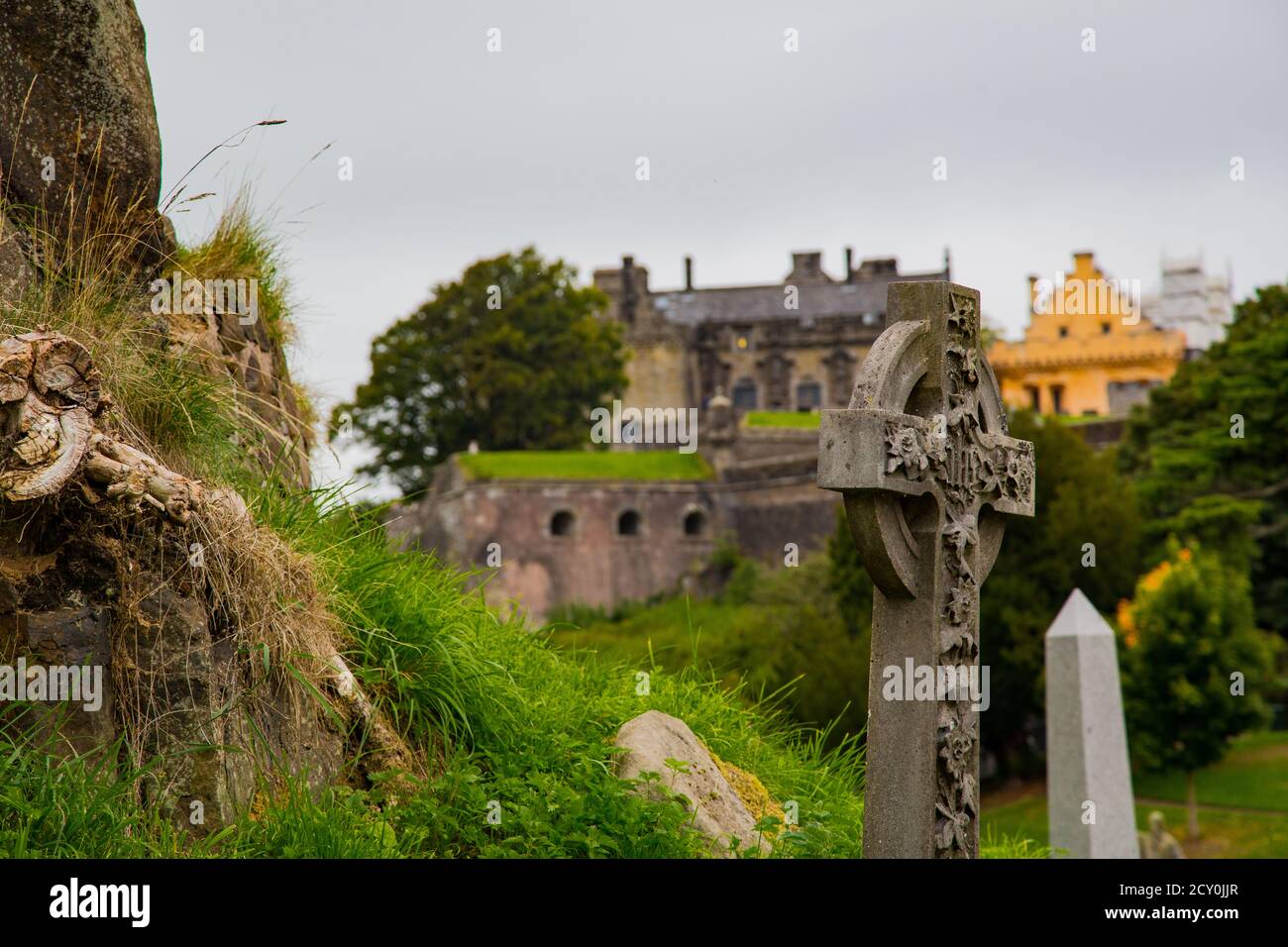 Beautiful gothic cross shaped stone tombstone with old buildings in th ...