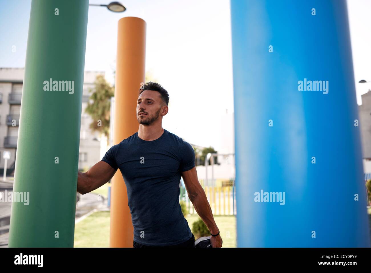 A young boy doing stretching exercises between coloured columns ...