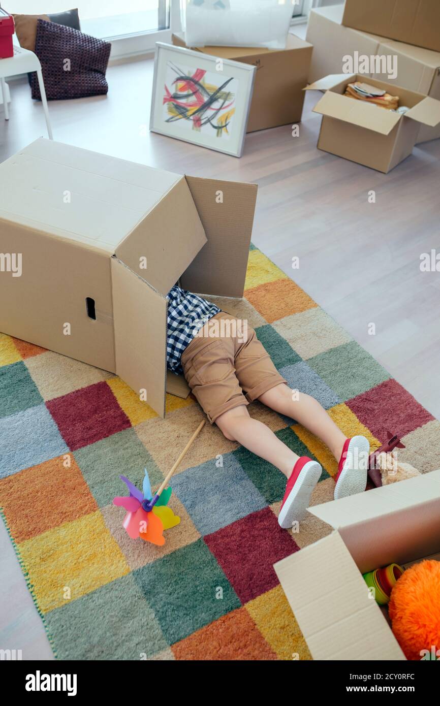 Boy playing inside a moving box while his father unpacks Stock Photo ...