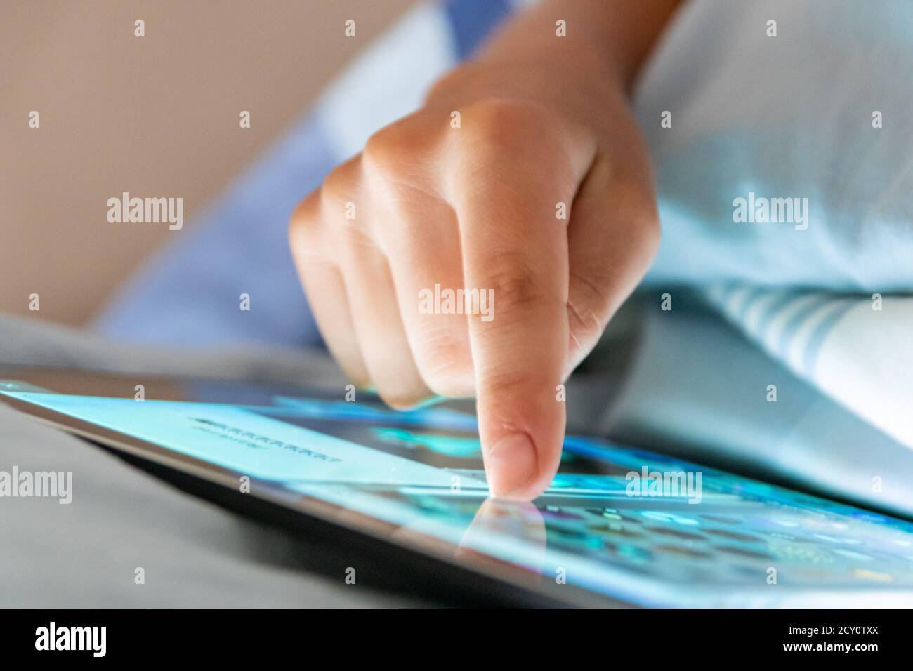 Child uses a tablet with his hand by fingertips before going to bed and ...