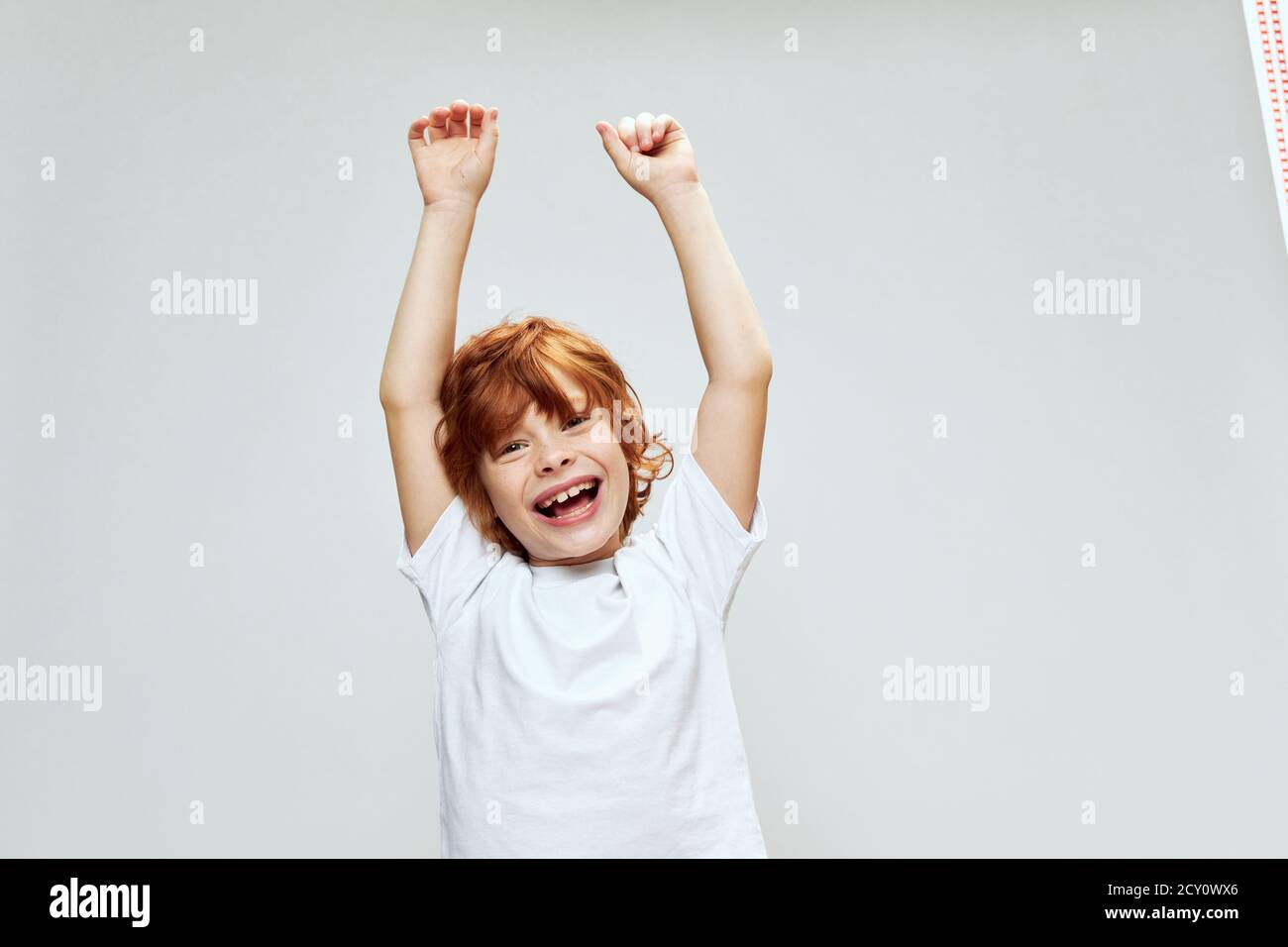 Red-haired boy with raised hands up smile cropped view white t-shirt ...