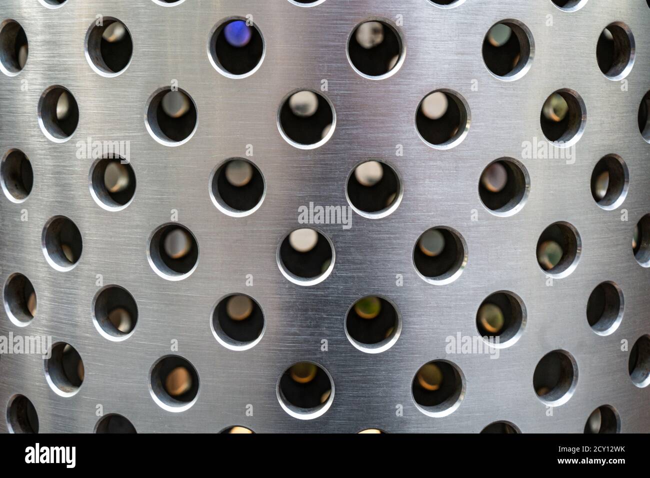 Curved stainless steel pole with pattern of round holes in it. Metal ...