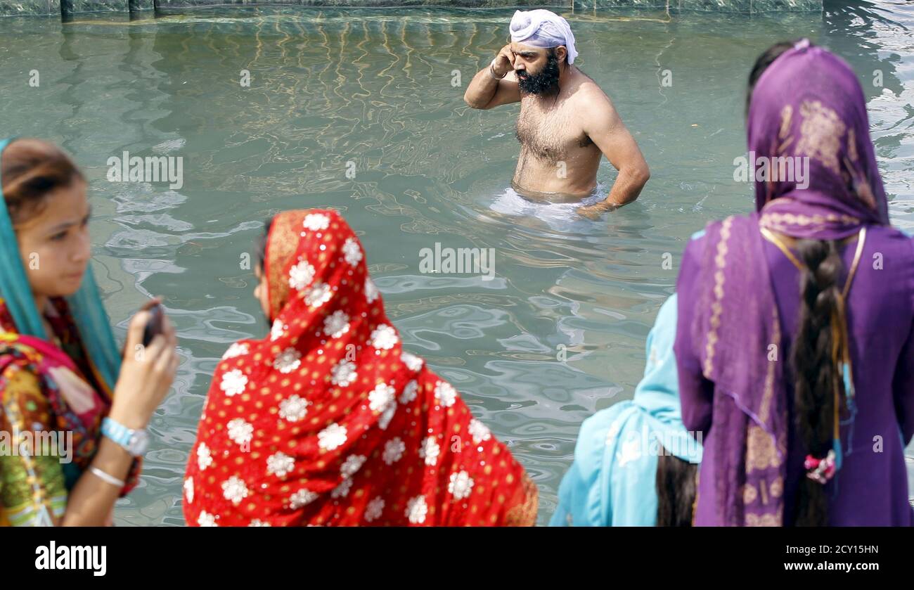 A Sikh devotee washes himself in the holy water at Panja Sahib in ...
