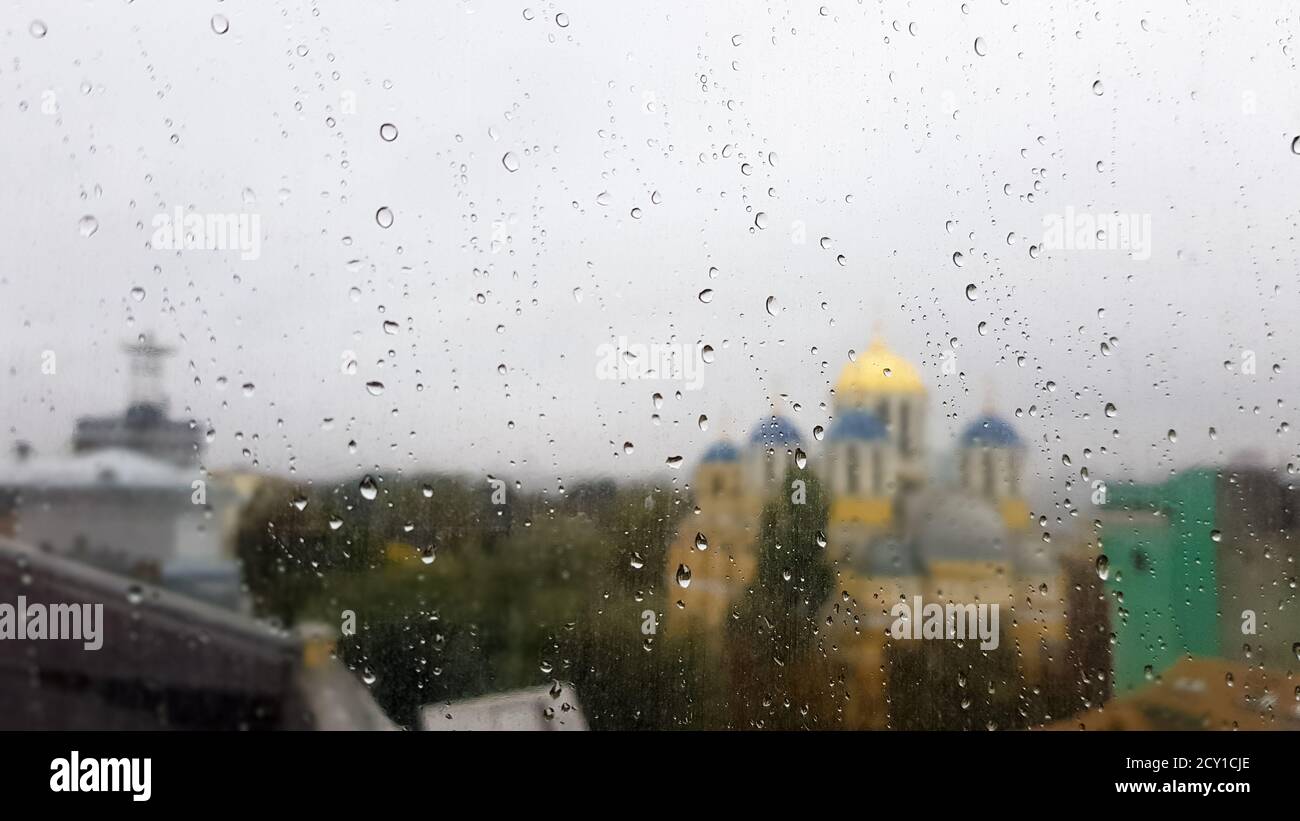 Wet window with drops on the background of the autumn city in cloudy ...
